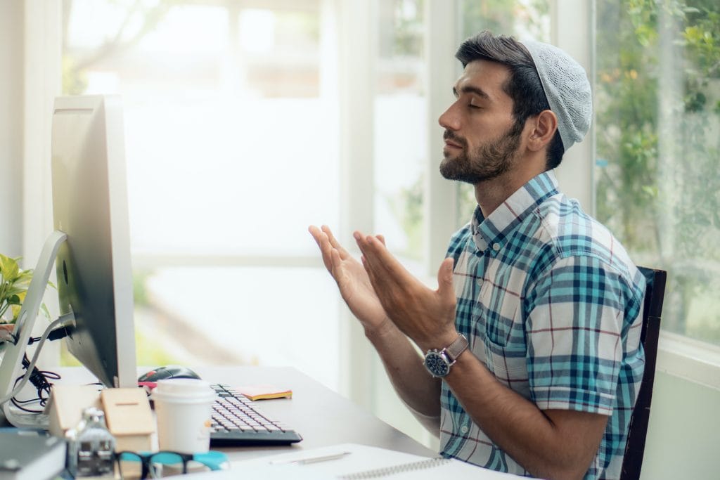 Man praying while at work desk - Converge
